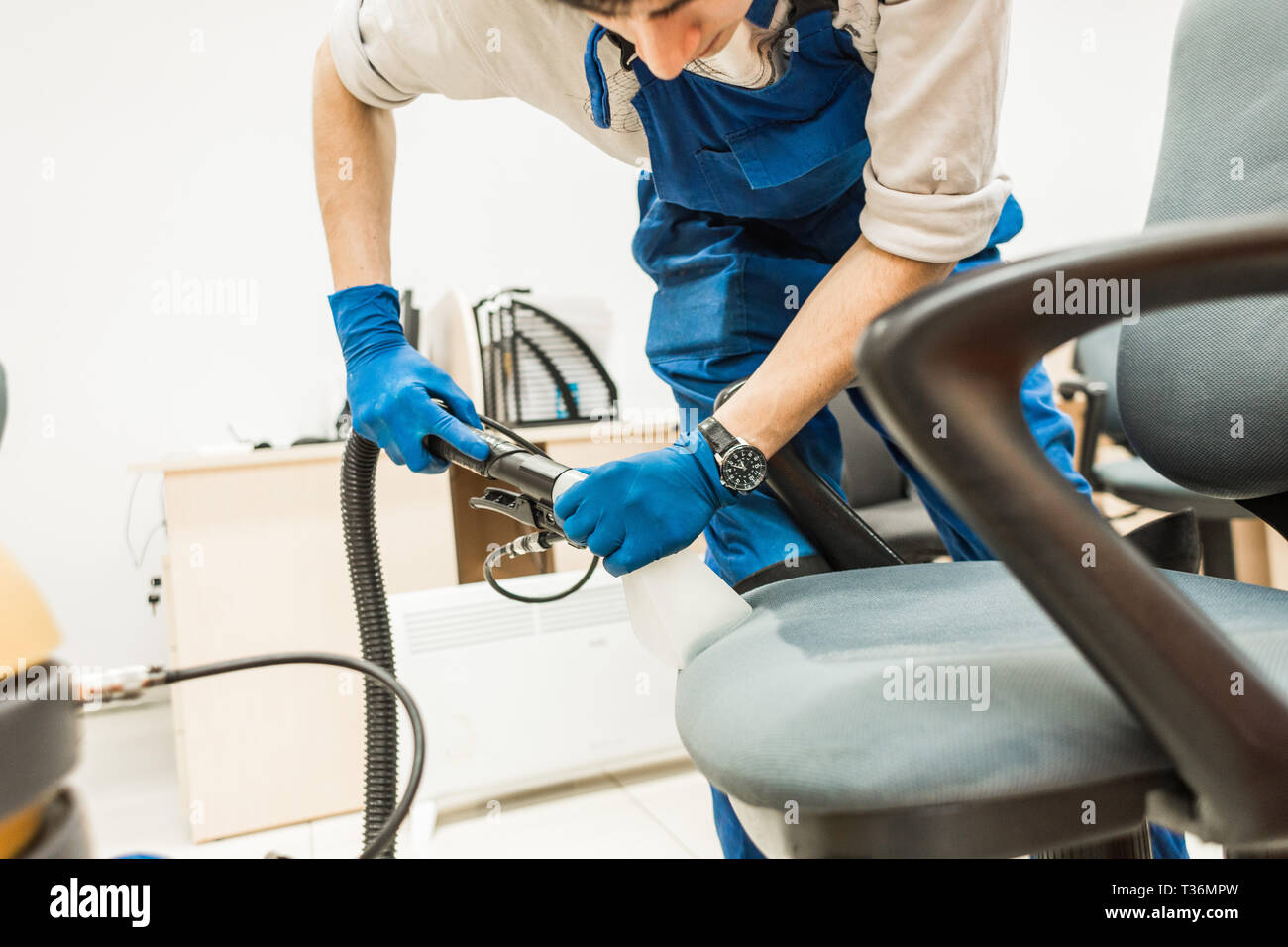Cleaning service. Young man in workwear and rubber gloves cleans the ...