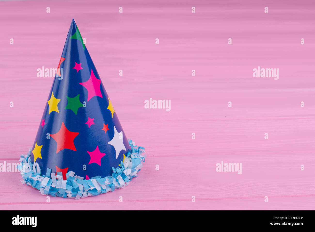 Blue party hat with stars pattern. Cardboard party cap on pink wooden ...