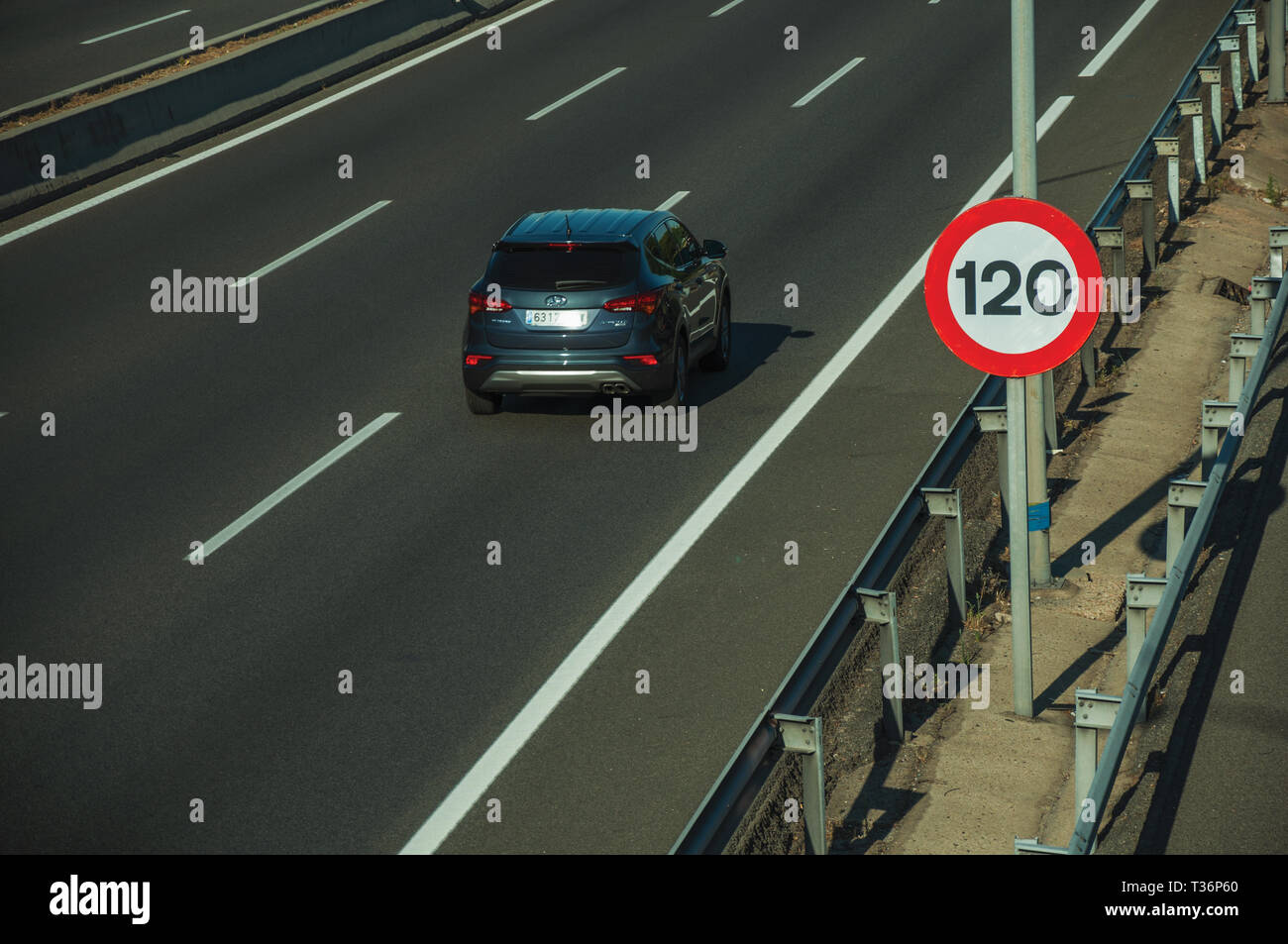 Lonely car passing through highway and SPEED LIMIT signpost, on sunset ...