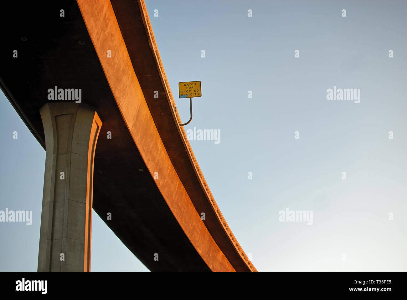 Concrete freeway ramp curving across the page in the afternoon sun ...