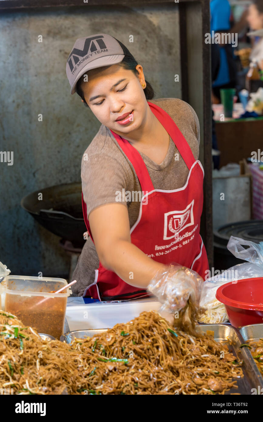 a street food trader selling thai spicy snacks at an evening market ...
