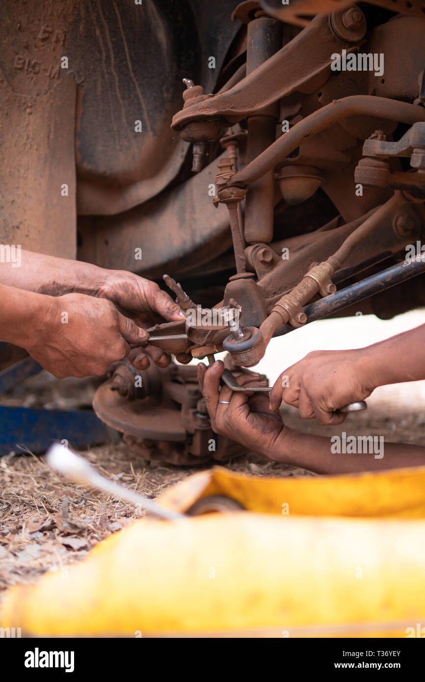 Hands of mechanic fixing wishbone control arm of the truck part to ...