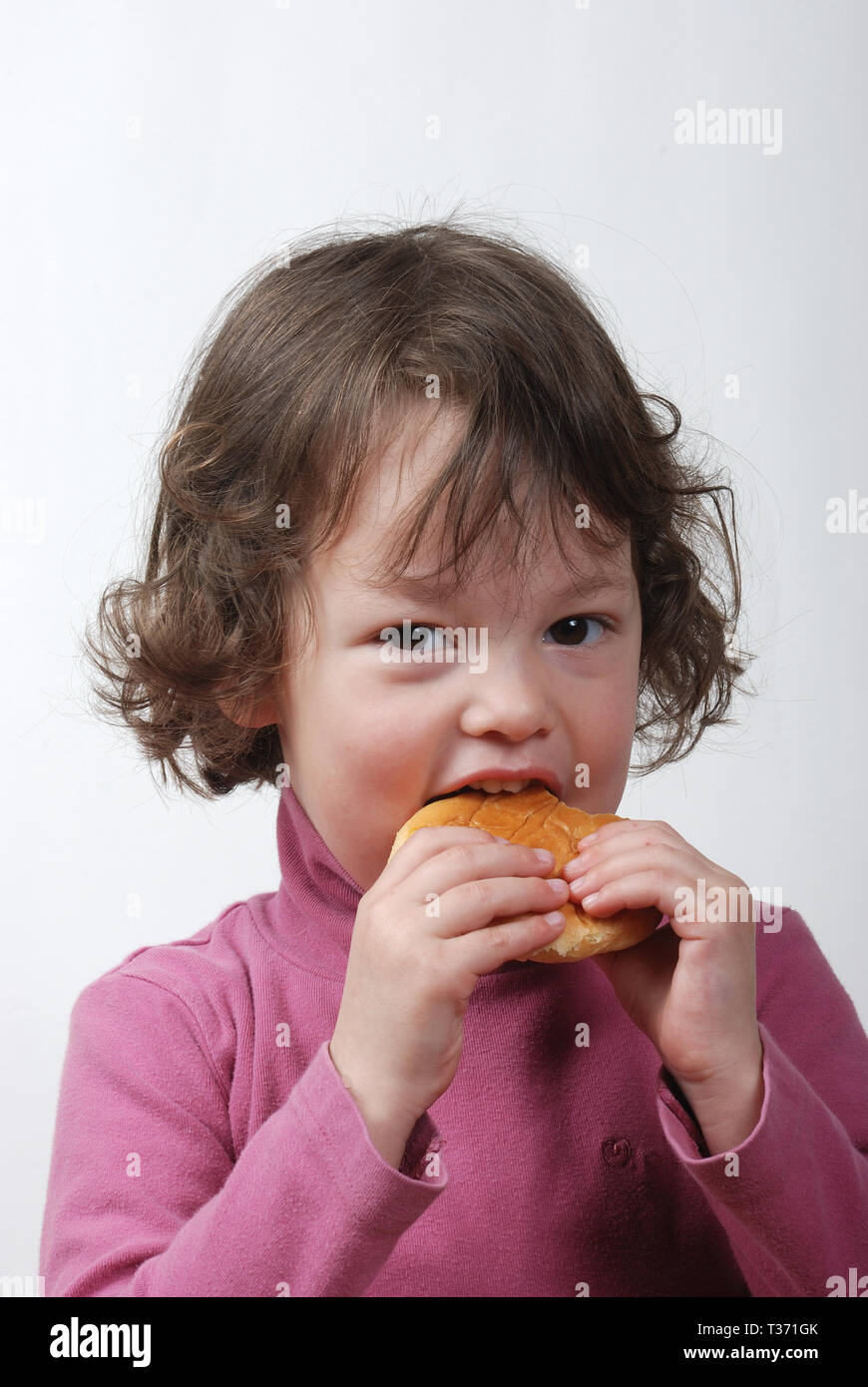 A young girl eating a bun Stock Photo - Alamy