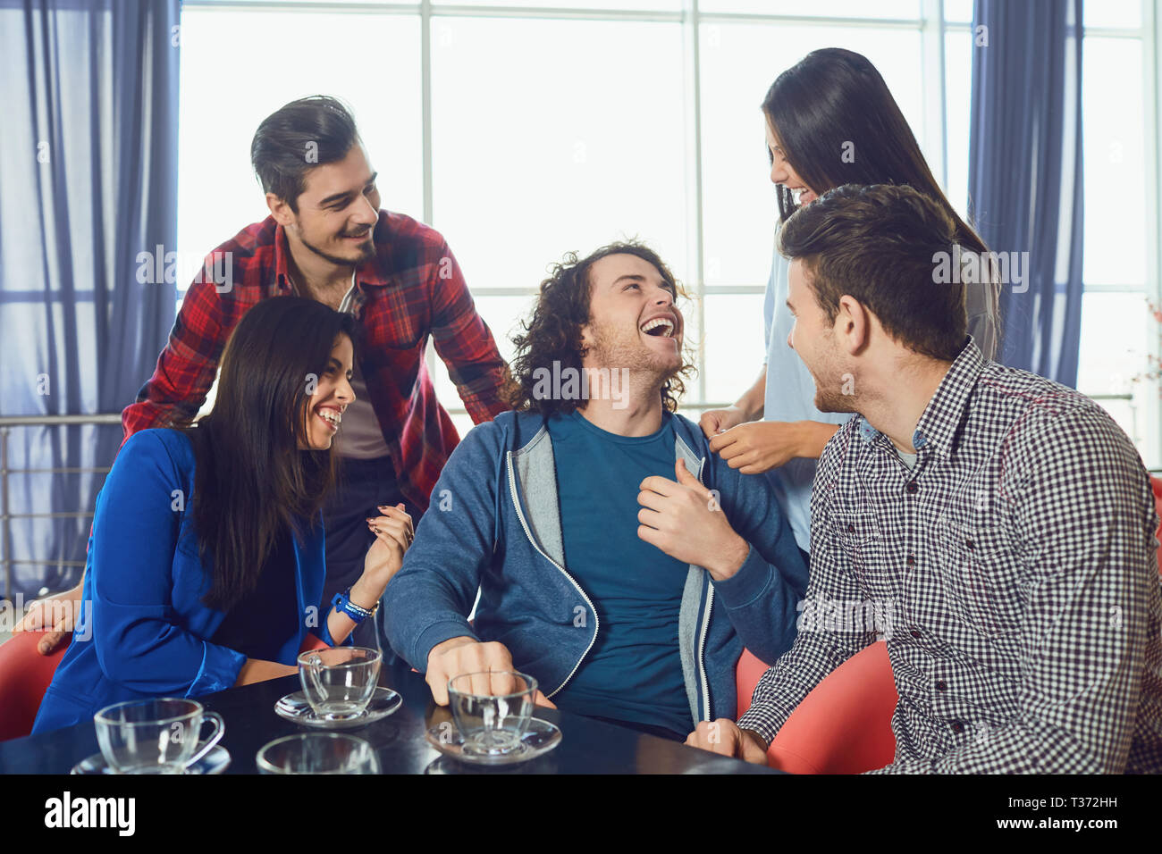 Funny friends talk and laugh in a cafe Stock Photo - Alamy