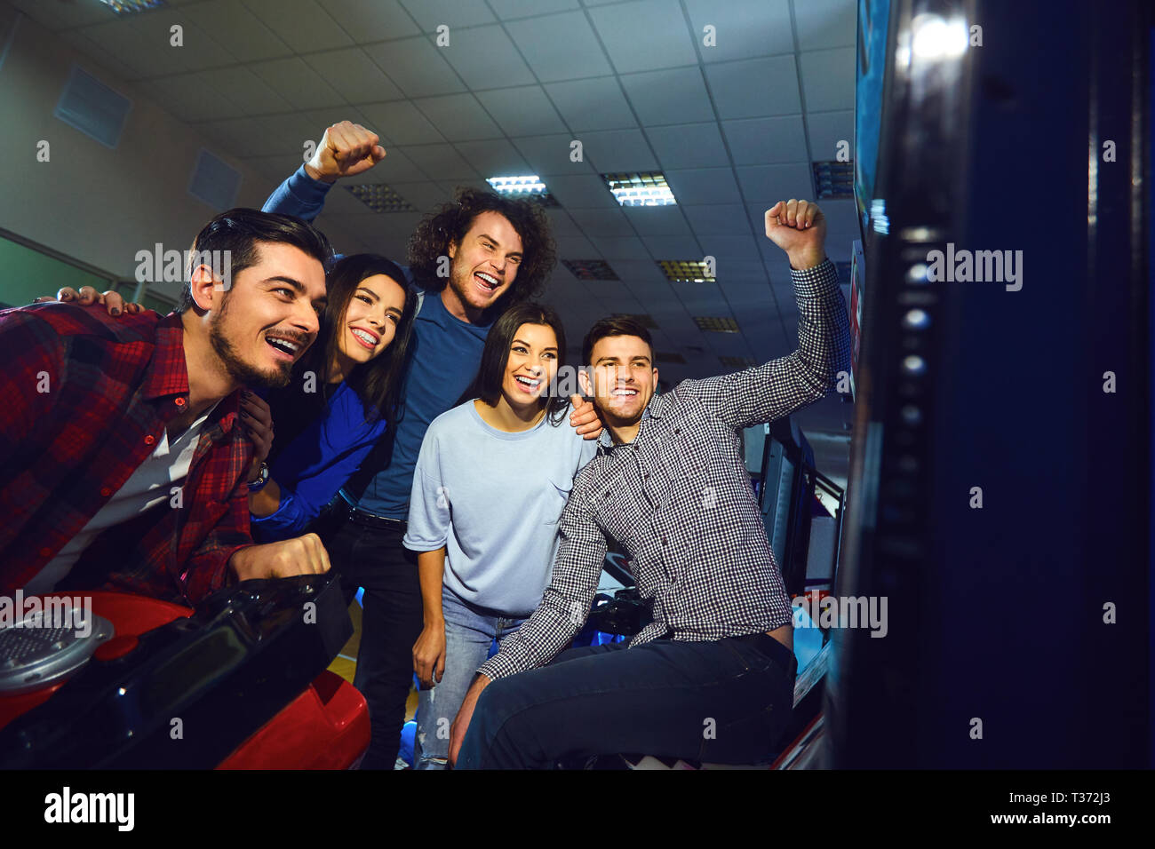 A group of friends playing arcade machine Stock Photo - Alamy