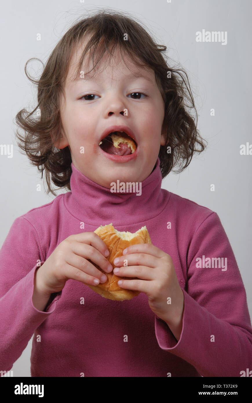 A young girl eating a bun Stock Photo - Alamy