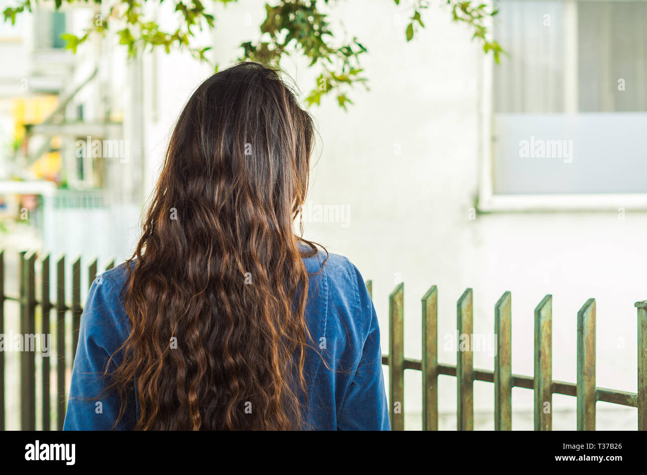 Authentic young woman outdoors turned with her back. Urban scene Stock ...