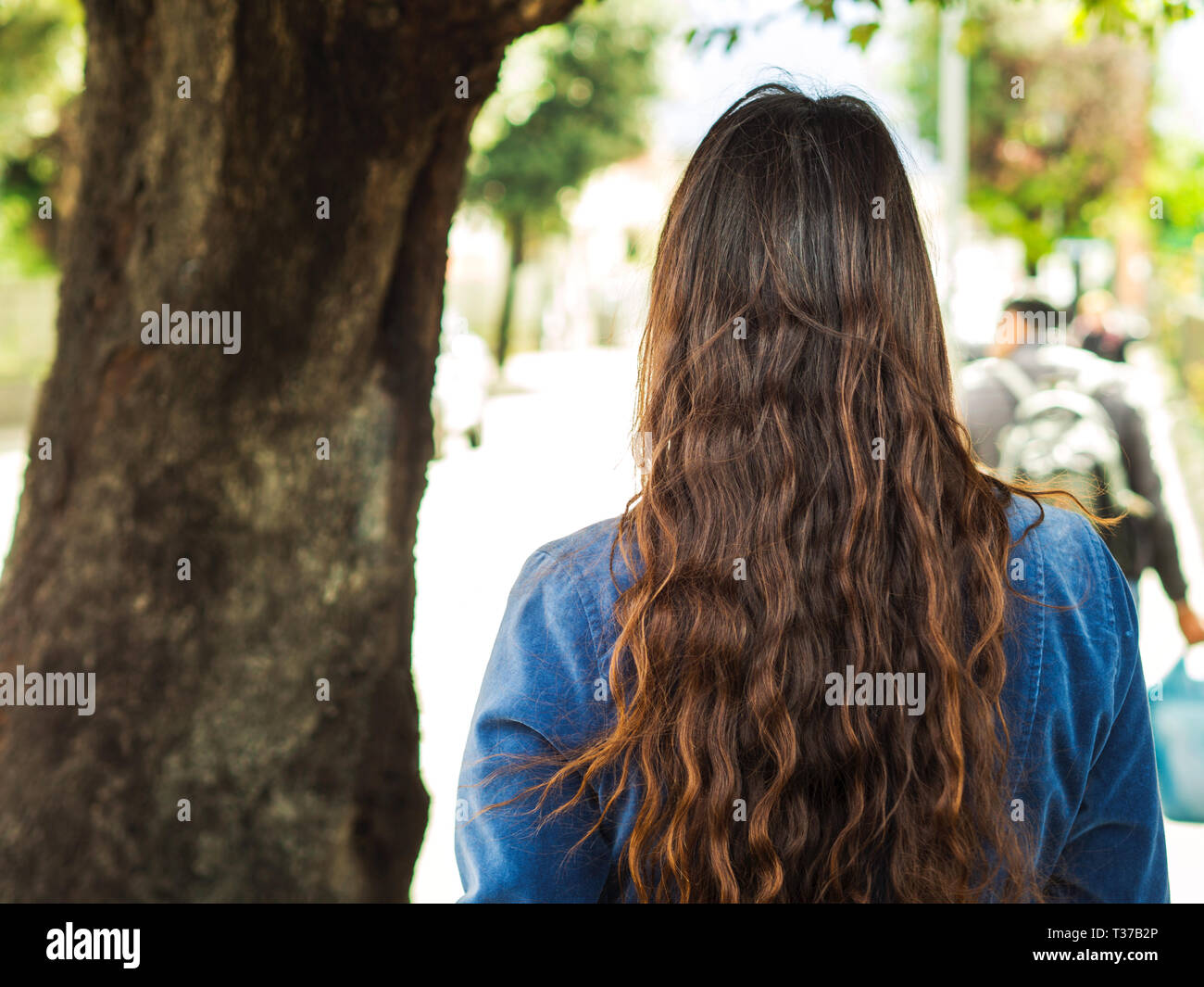 Authentic young woman outdoors turned with her back. Urban scene Stock ...