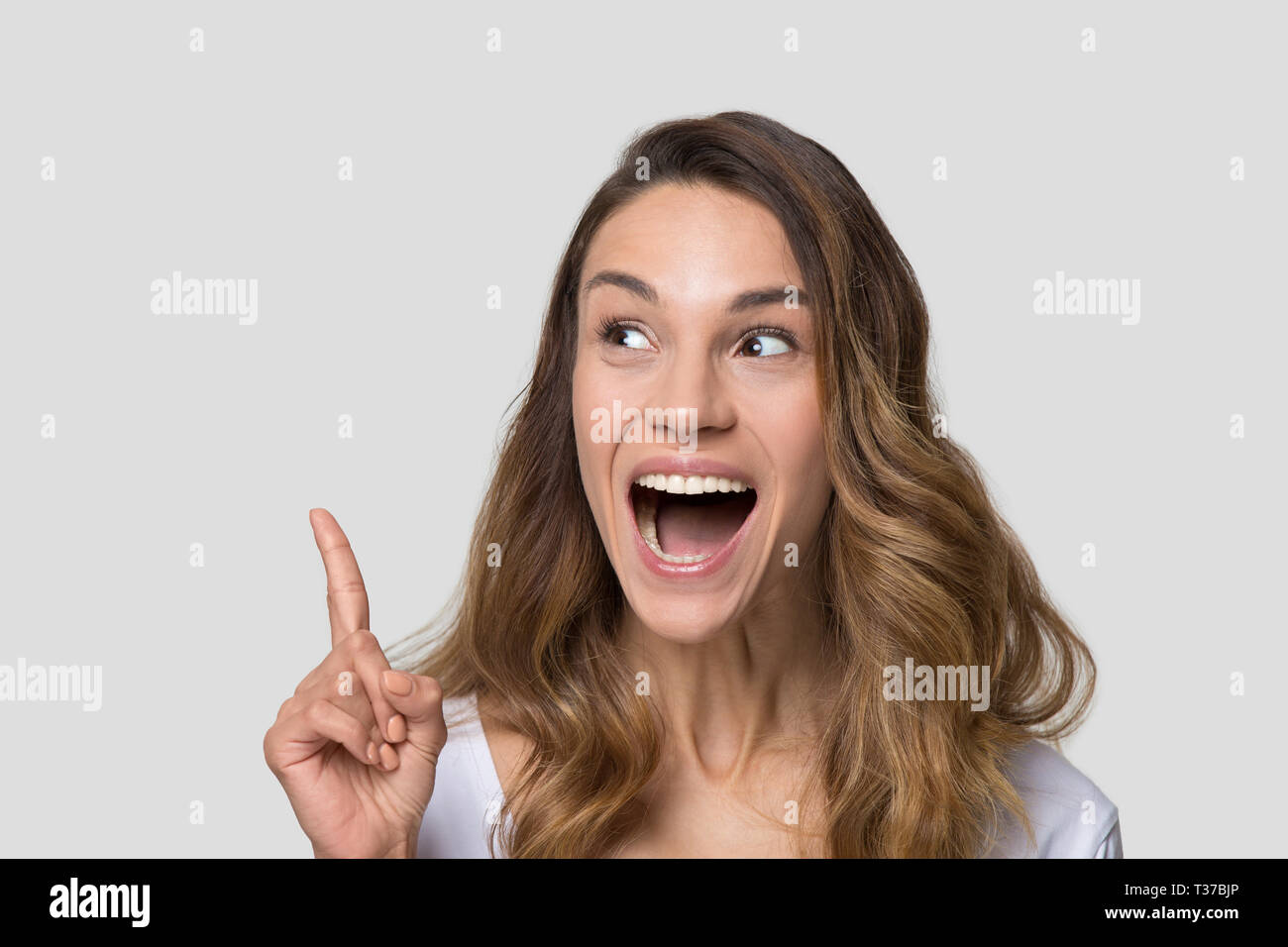 Astonished millennial woman pointing finger above on copy space Stock ...