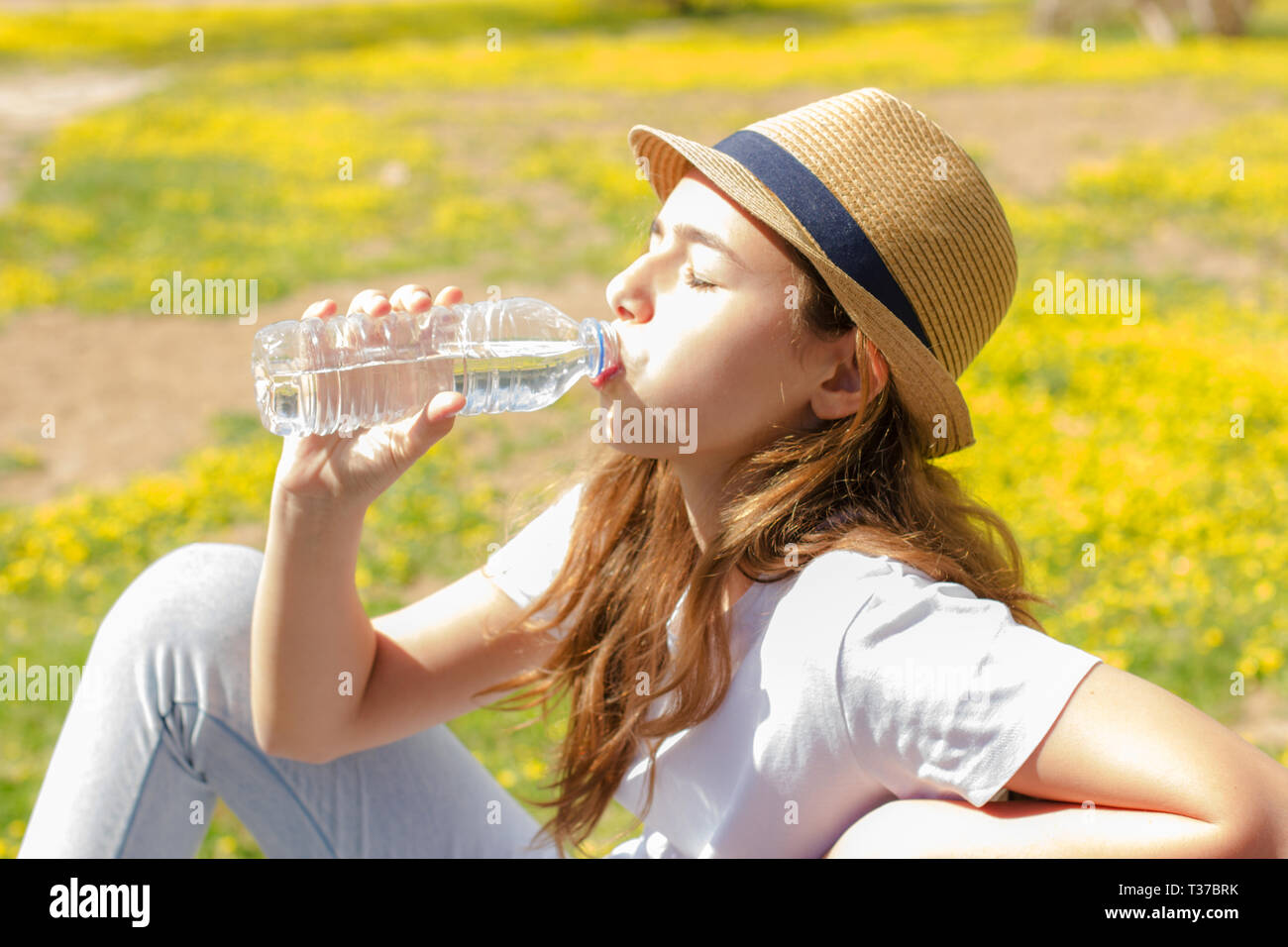 Beautiful teen girl drinks clean water from a plastic bottle on hot summer day Stock Photo - Alamy