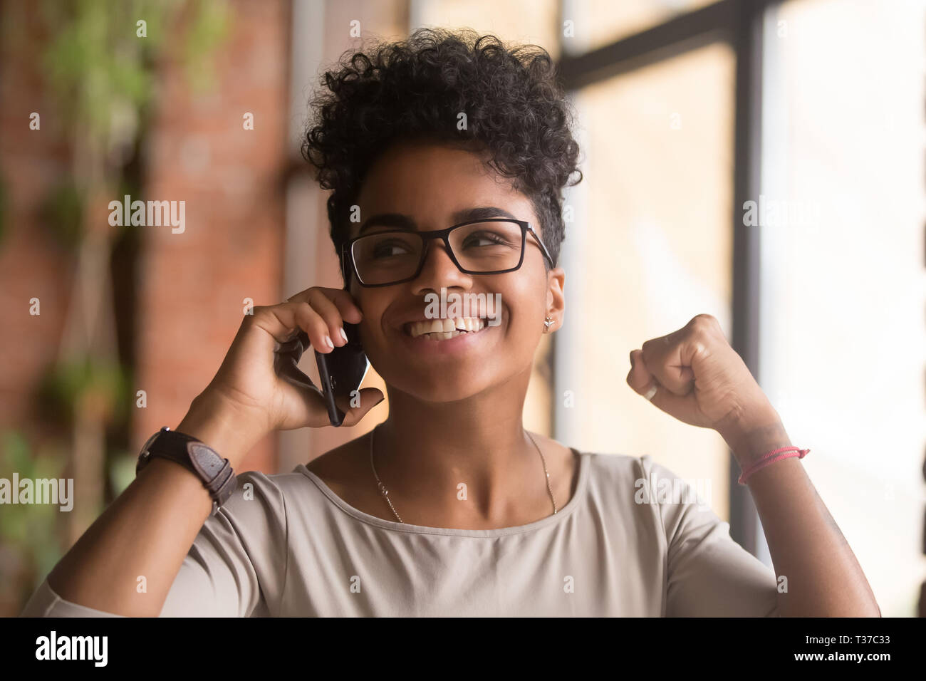 Excited african woman talking on phone happy about good news Stock ...