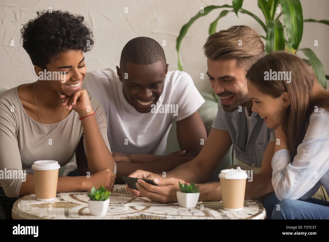 Friends laughing mobile device watching hi-res stock photography and ...