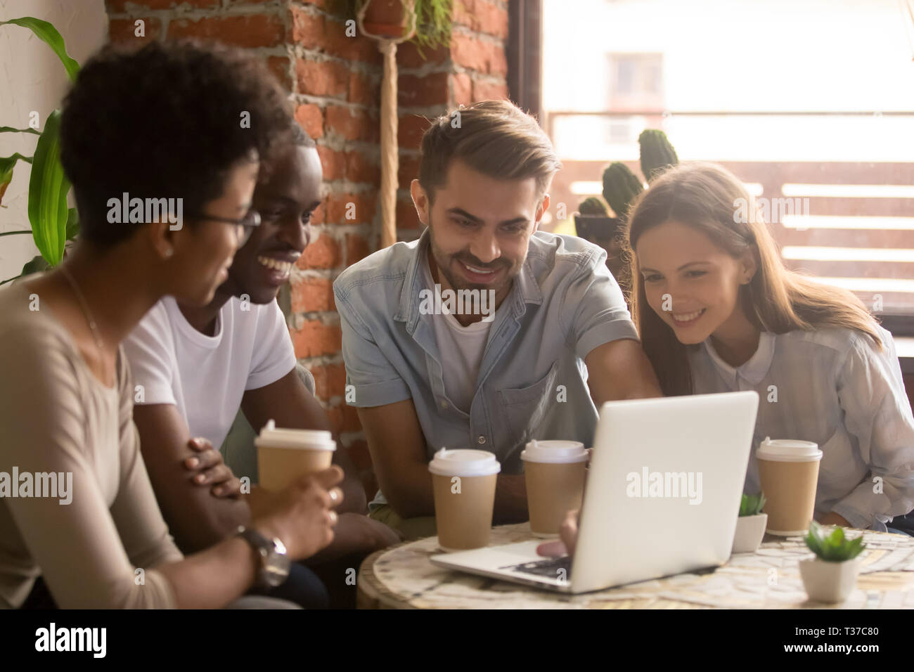 Happy diverse friends group looking at laptop watching comedy movie ...