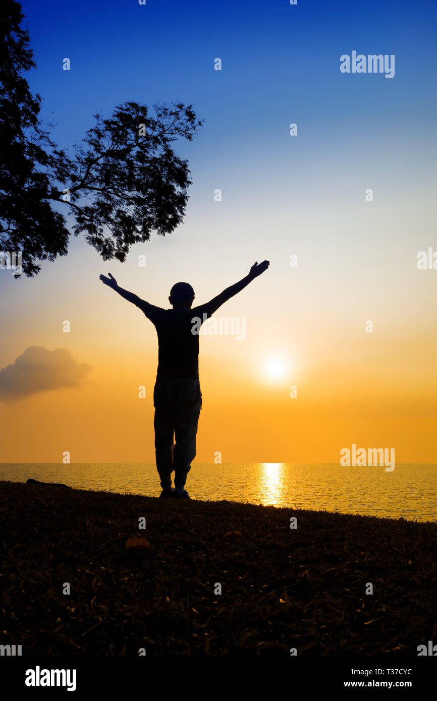 Man in silhouette open arms under the sunrise at seaside. Vertical ...