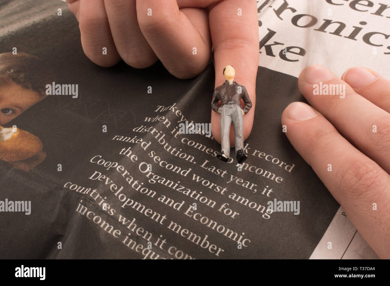 Hand holding a human figure on a newspaper Stock Photo - Alamy