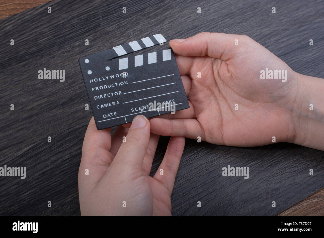 Hand holding movie clapper on a dark background Stock Photo - Alamy