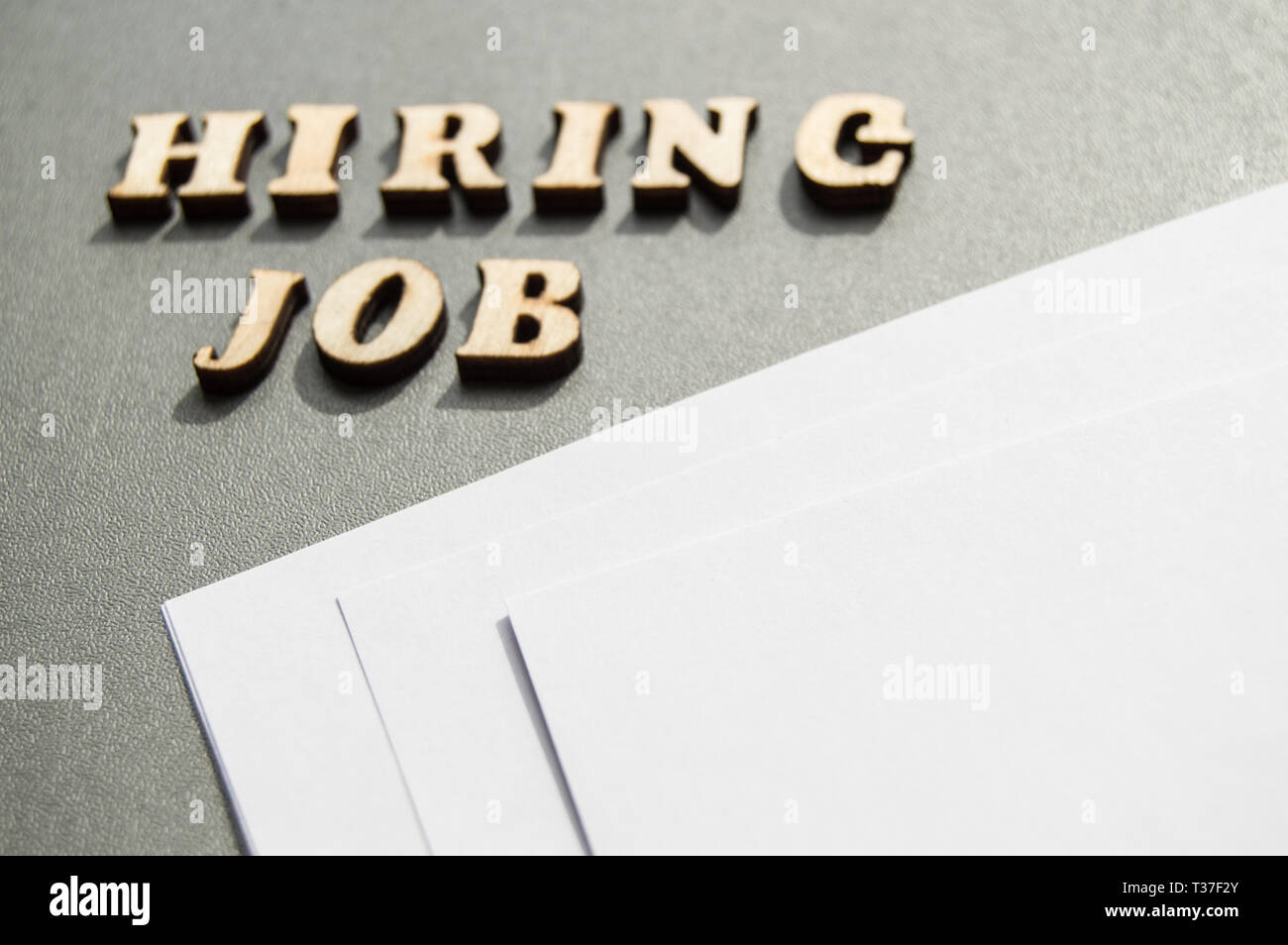 Hiring JOB is written in wooden letters on a gray background, near ...