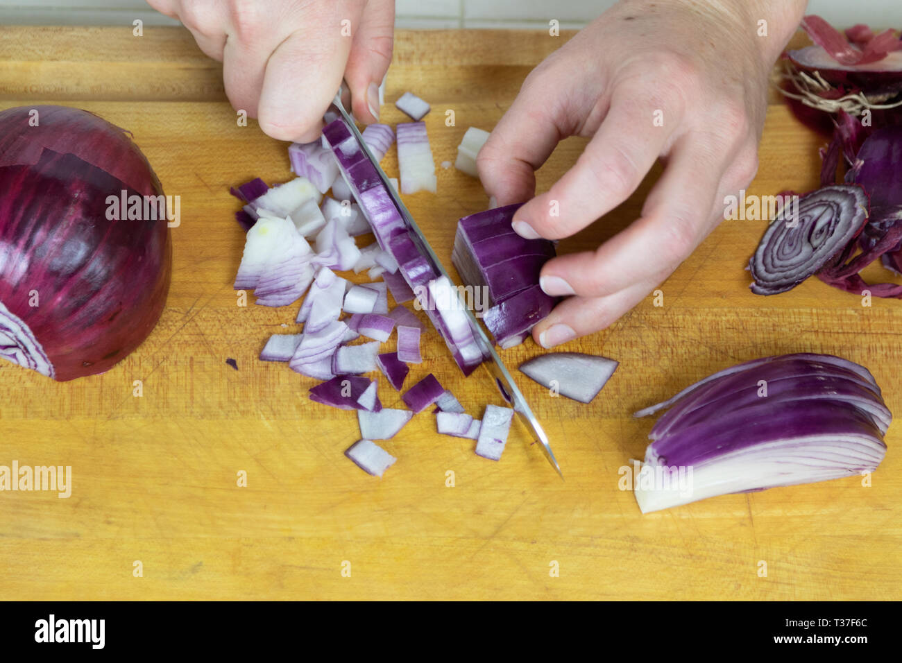 Close up overhead view of female hands with fingers curled dicing ...