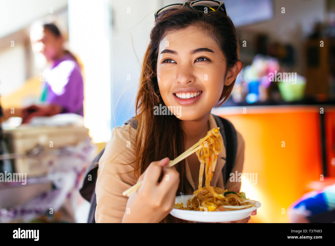 Young Asian tourist woman eating pad thai noodle, traditional street ...