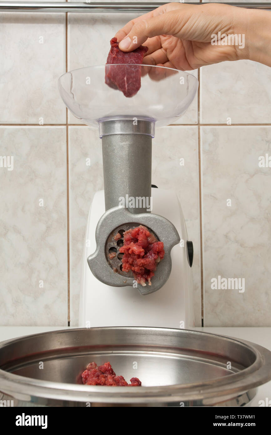 hand of woman making forcemeat with electrical meat grinder in the ...