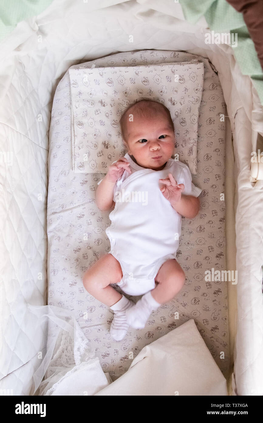 Newborn baby boy in bed. New born child in white bodykit lying in light ...