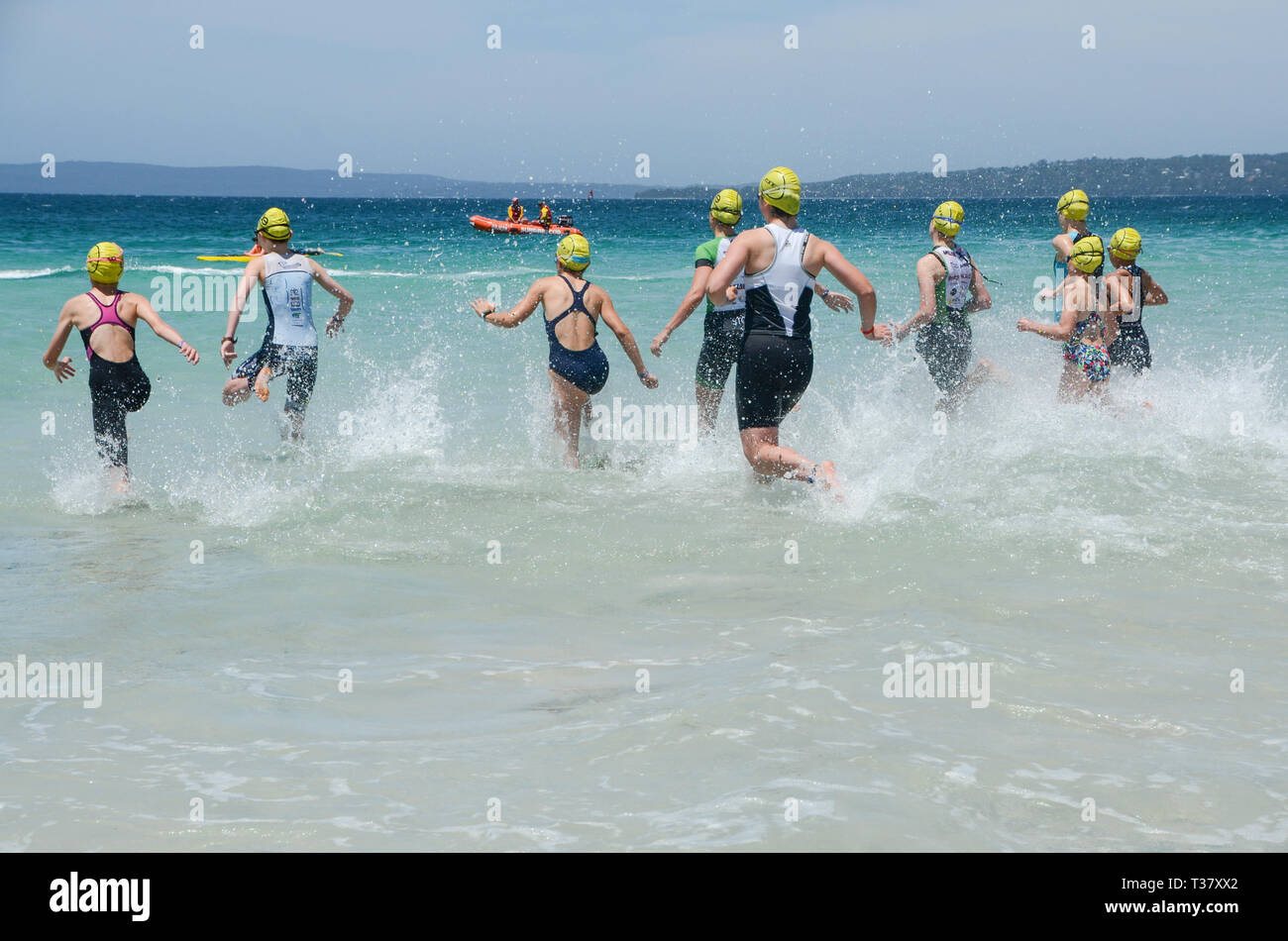 Group of female athletes running into the surf for swim portion of ...