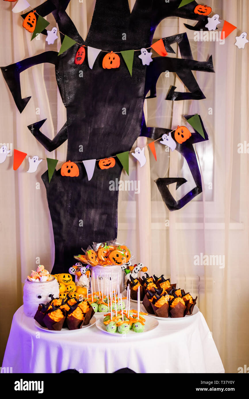 Candy bar with sweets for the celebration of Halloween. Huge black tree ...