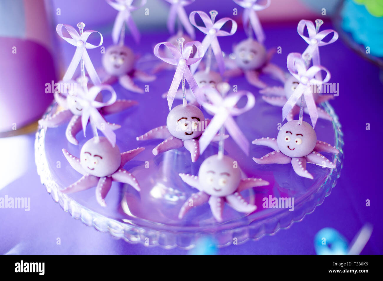 Purple cake pops funny octopuses shared on the glass round plate and ...
