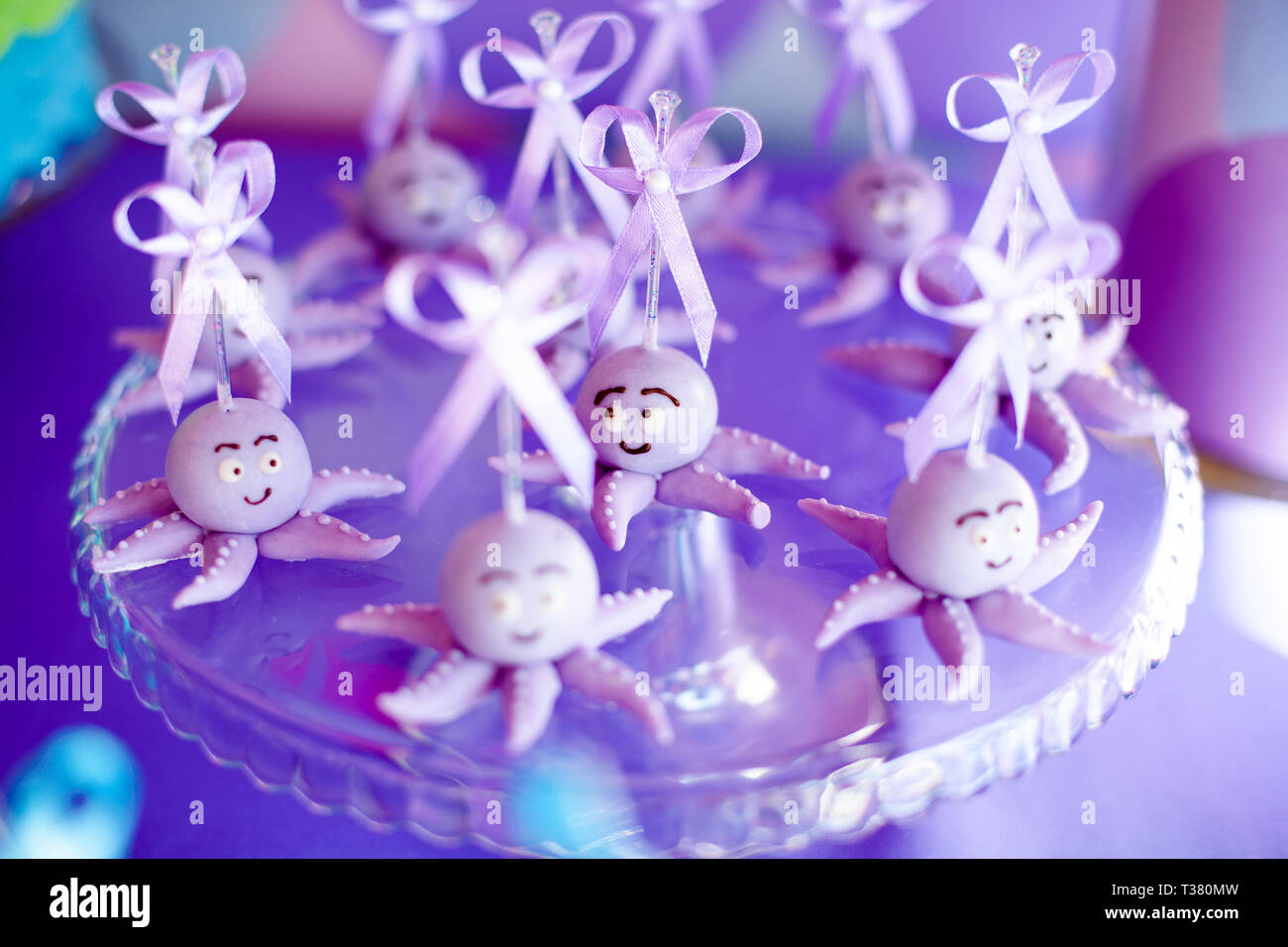 Purple cake pops funny octopuses shared on the glass round plate and ...