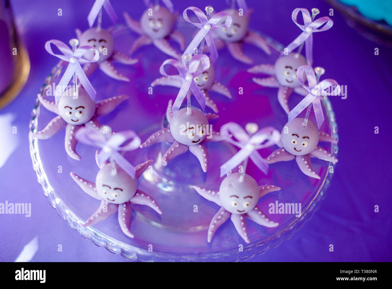 Purple cake pops funny octopuses shared on the glass round plate and ...