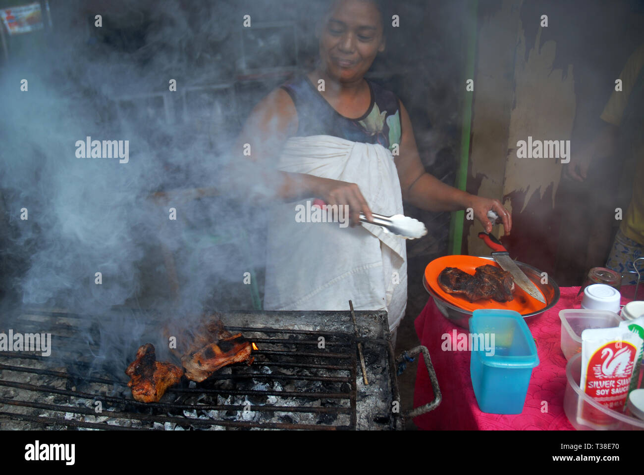 Lady cooking meat to sell at food stall, Samal, Philippines Stock Photo ...