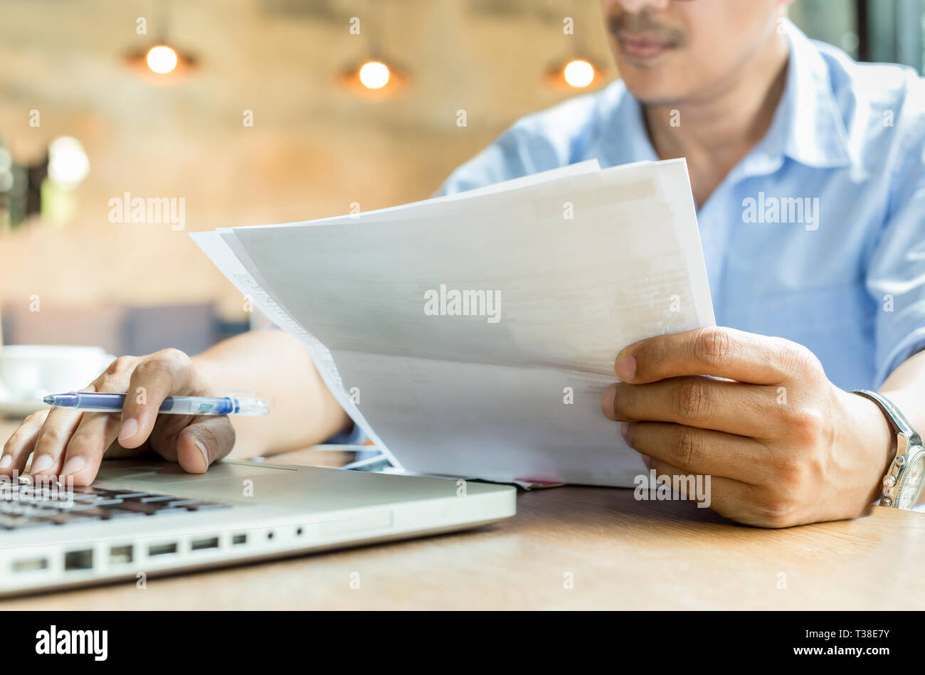 Businessman hands holding document paperwork and pen working on laptop ...