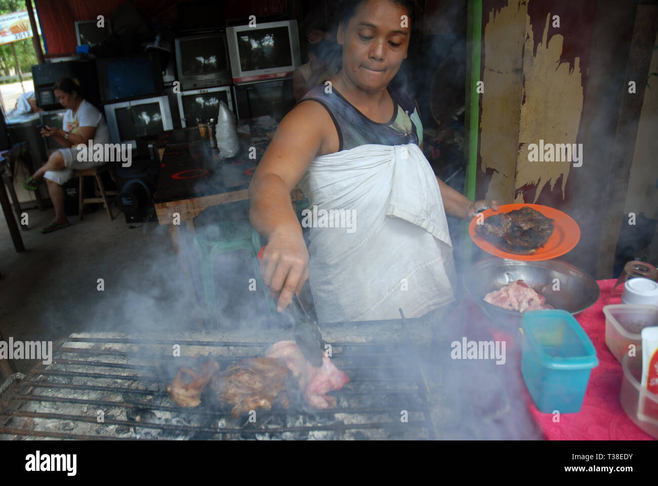 Lady cooking meat to sell at food stall, Samal, Philippines Stock Photo ...