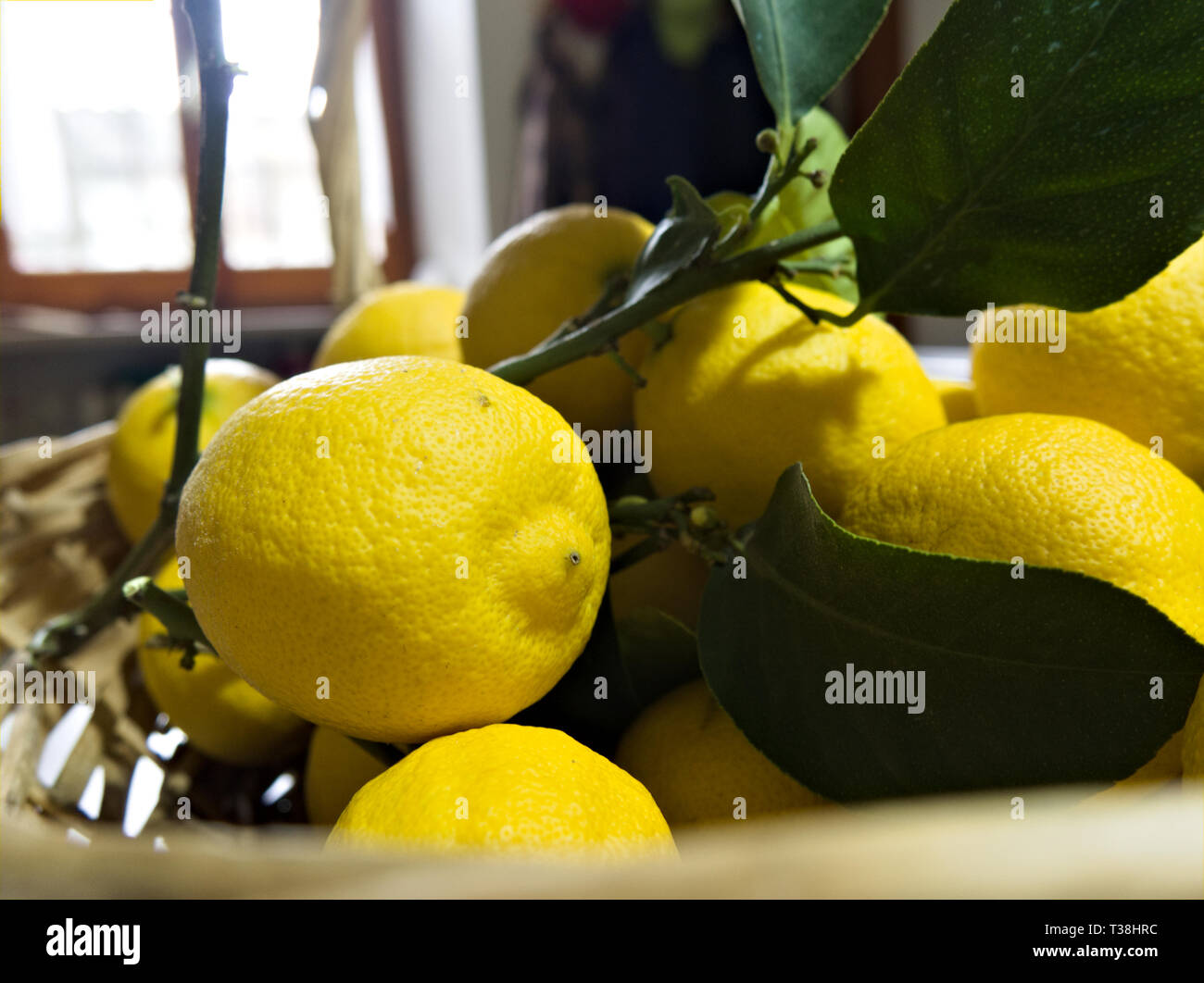 Fresh lemons with leaves in a wicker basket in a italian rustic kitchen ...