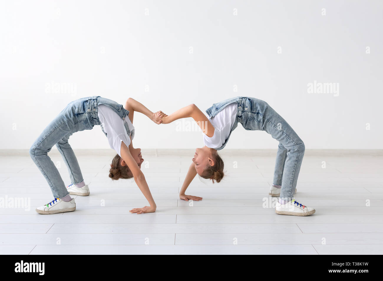 Family and sport concept - Two acrobat twin girls are standing on the ...
