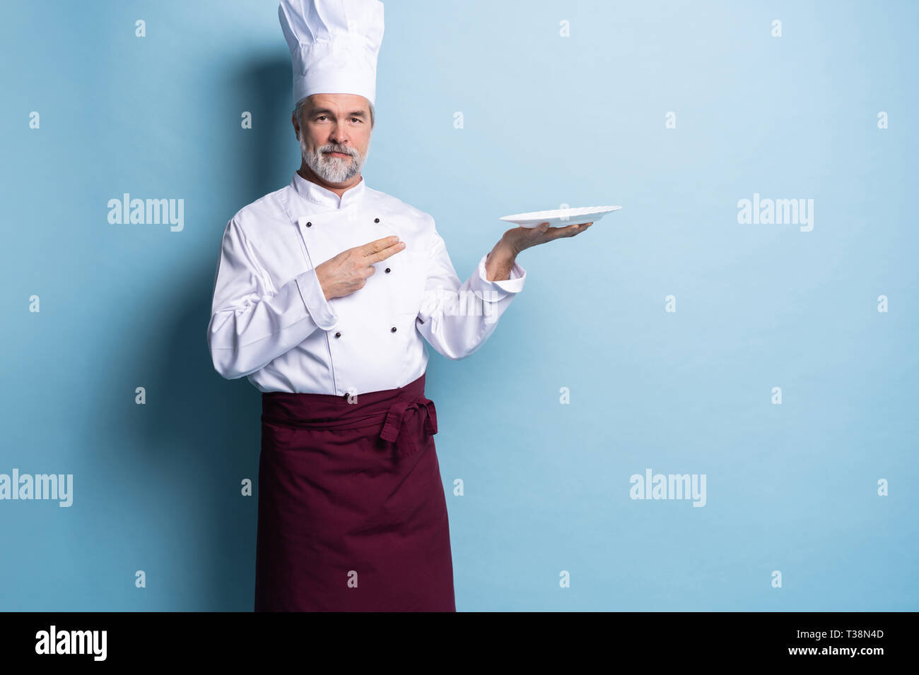 Portrait of a professional chef holding an empty plate isolated on ...