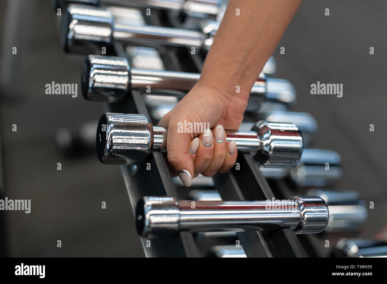 woman hand takes dumbbell form rows of dumbbells in the gym Stock Photo ...