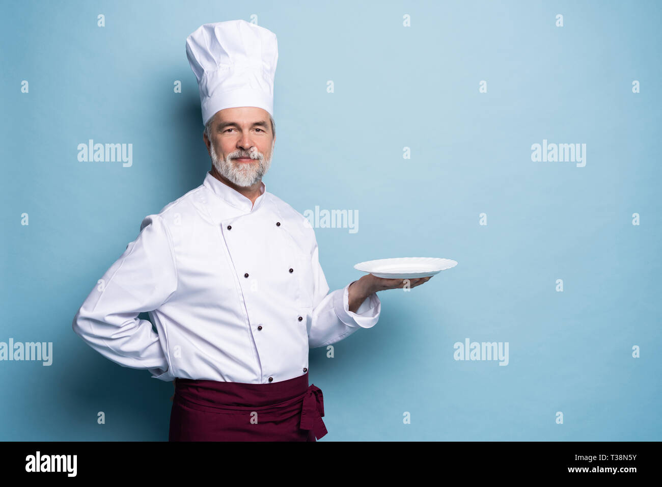 Portrait of a professional chef holding an empty plate isolated on ...