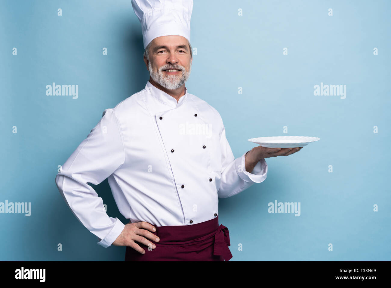 Portrait of a professional chef holding an empty plate isolated on ...