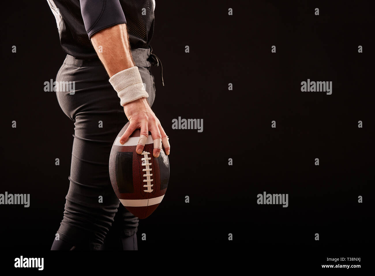 The middle part, of an American football player in black uniform with a ...