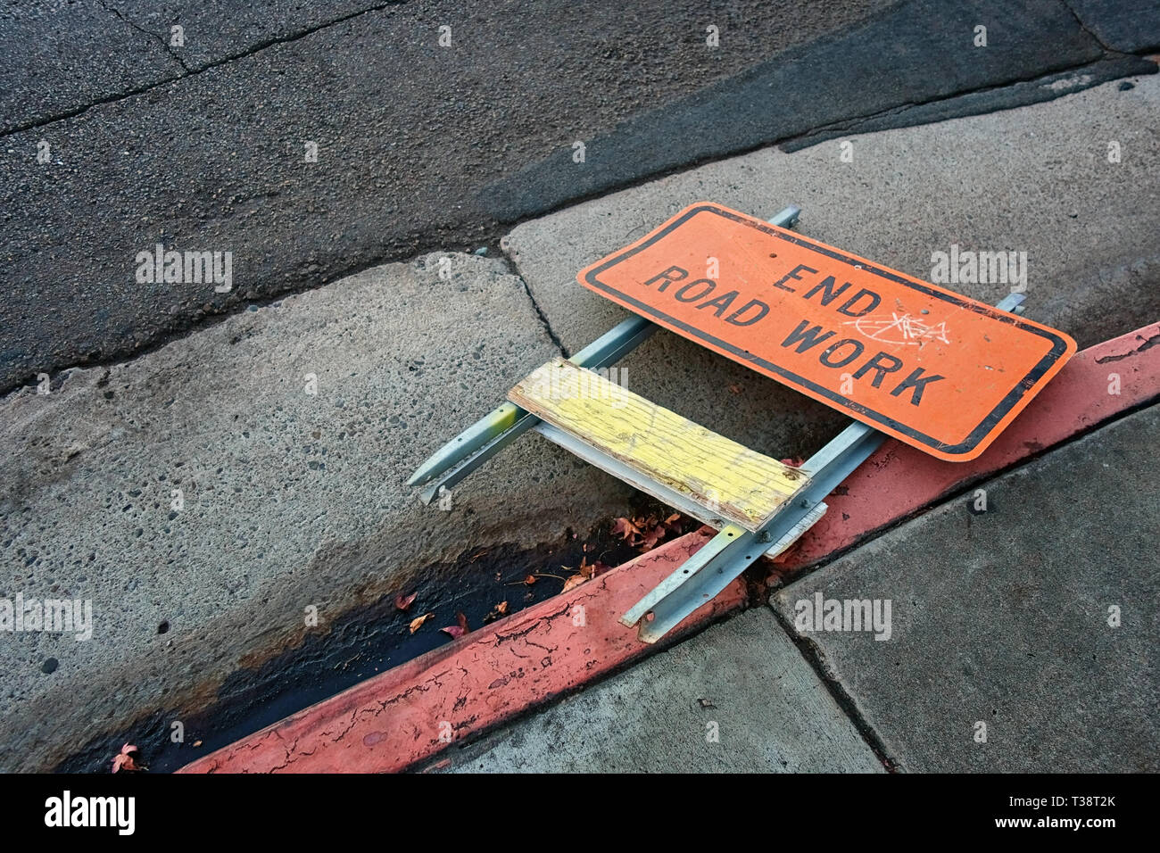 An orange end road work sign laying in the gutter Stock Photo - Alamy