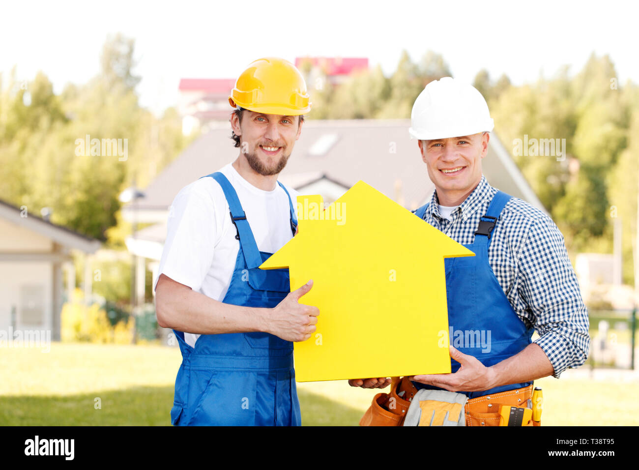 Construction workers showing house model symbol and friendly smiling ...