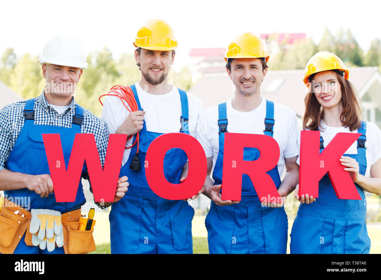 Happy workers in uniform holding work letters Stock Photo - Alamy
