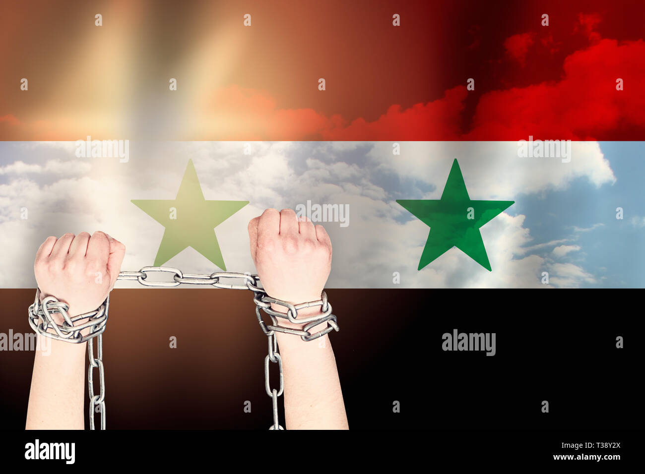 Two hands shackled a metal chain on the background of the Syria flag ...