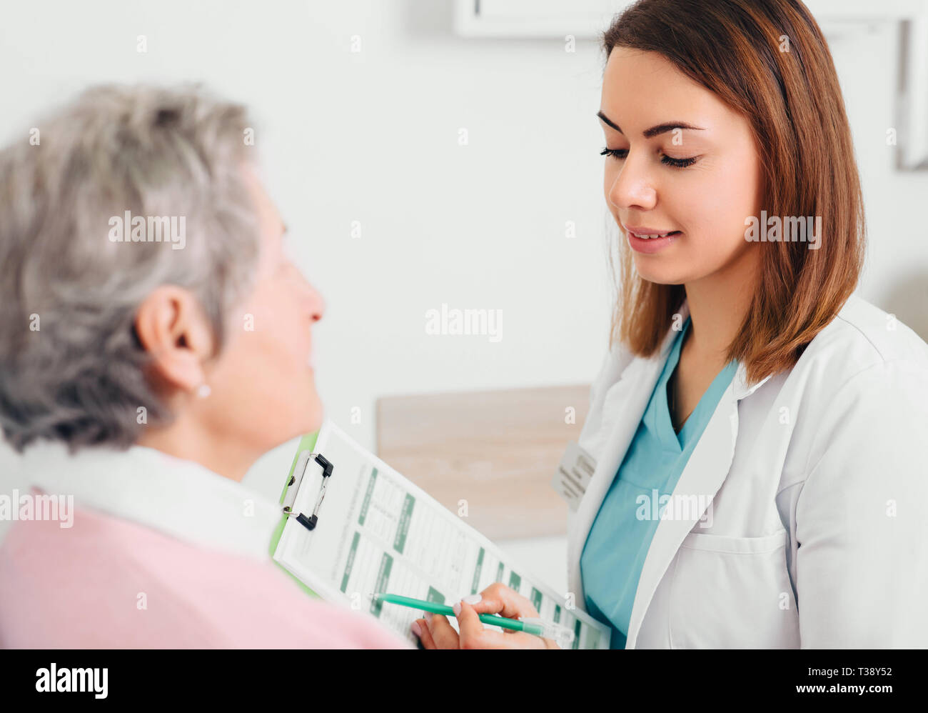 Female doctor explaining to aged patient at office in hospital. Record ...