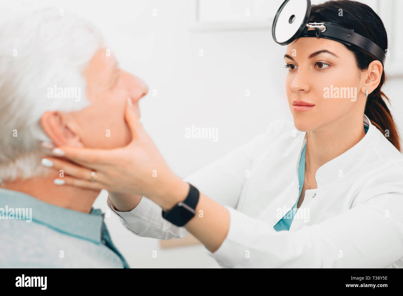 otolaryngologist doctor examining her patient, checking seniors man ...
