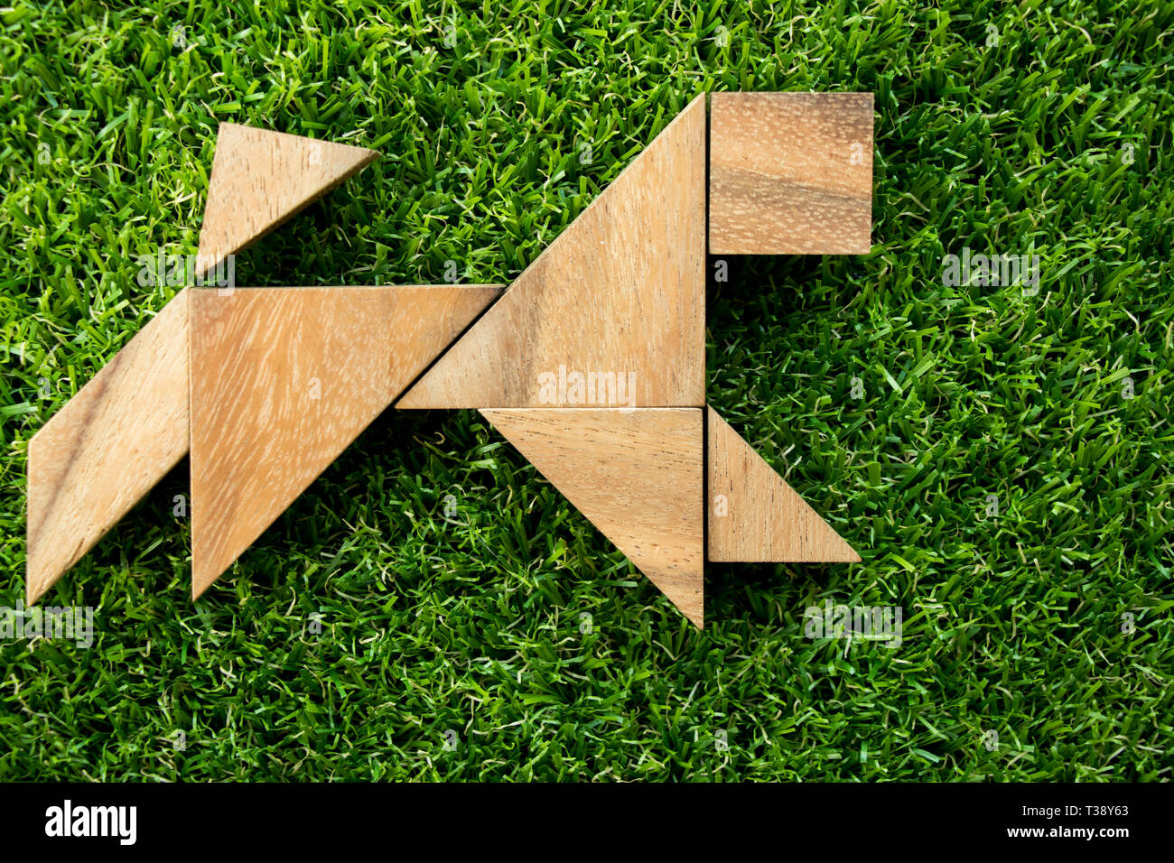 Wooden tangram puzzle in dog shape on artificial green grass background ...