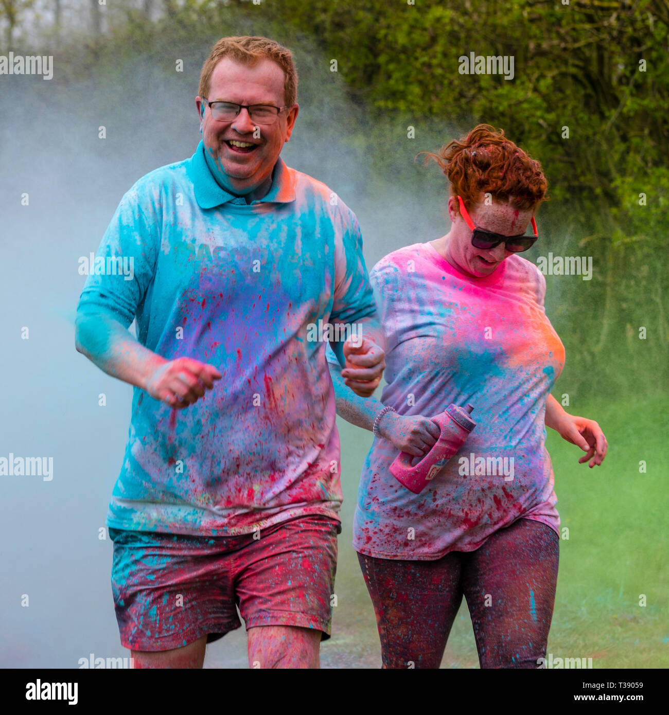 Adult couple running and laughing and being covered in paint on ...