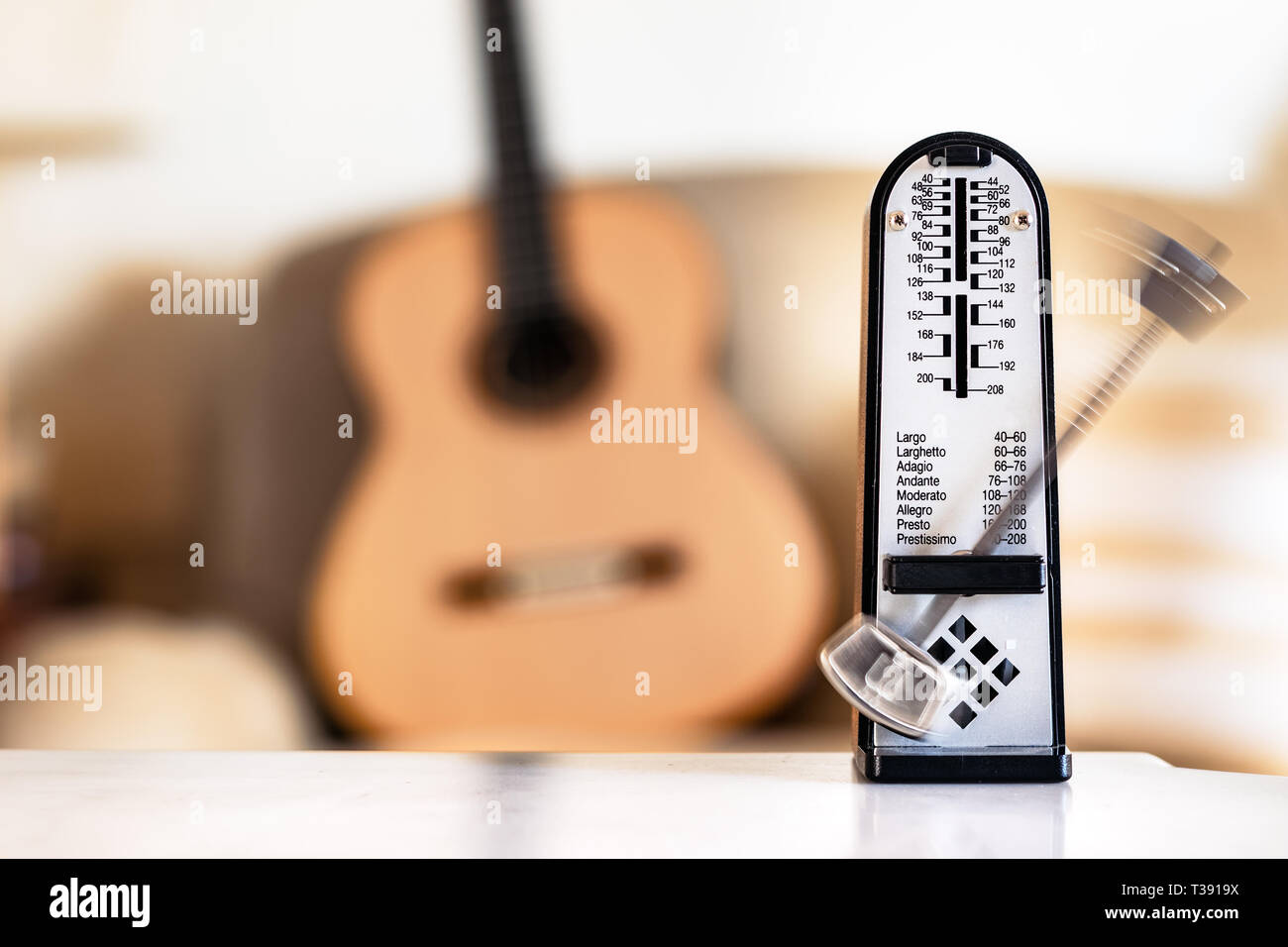 Mechanical metronome in motion, over a wooden classical acoustic guitar ...