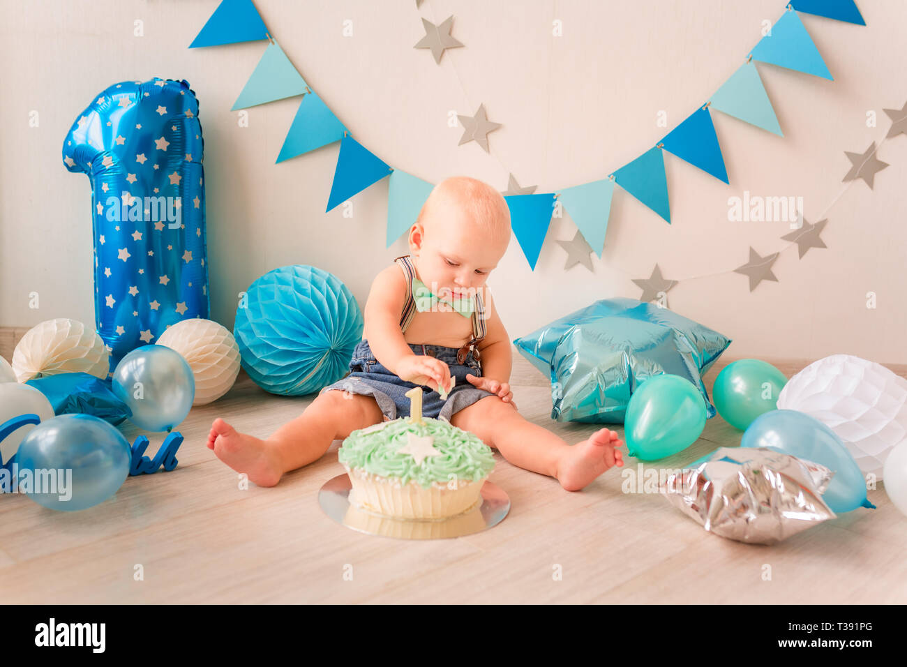 Adorable baby boy celebrating his first birthday. Smash cake party ...